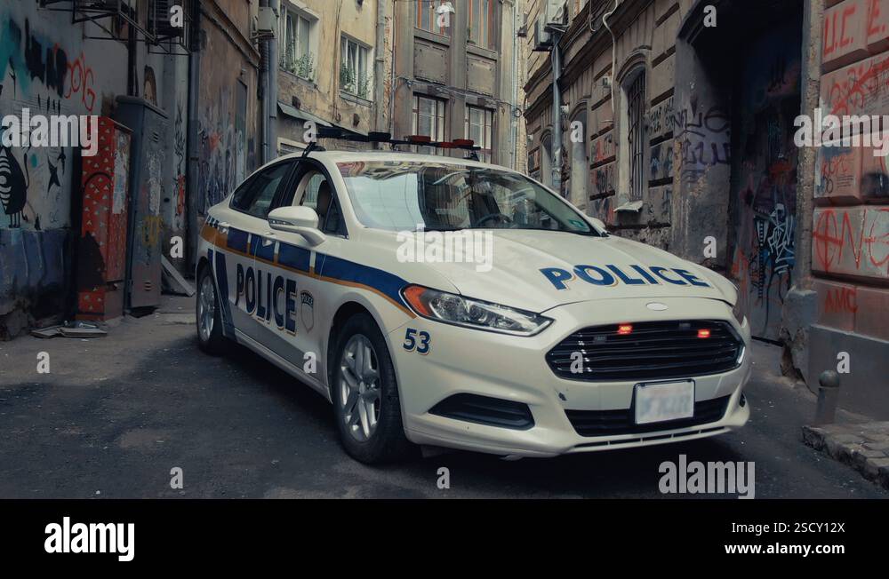 Drone zooming view of white police patrol car standing in tight old ...