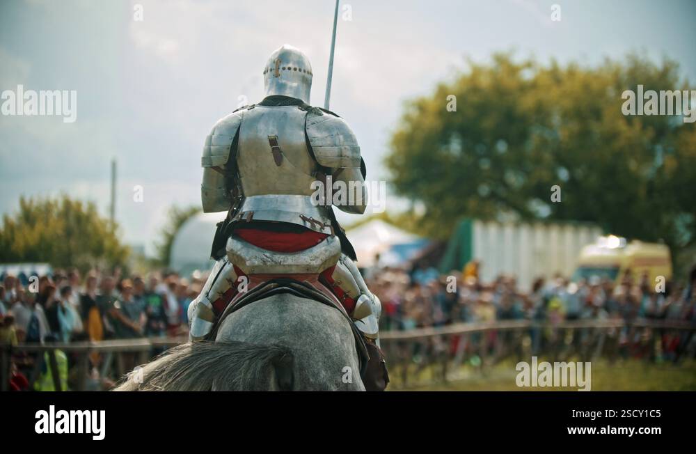 A man knight riding a horse around the battlefield and people watching ...