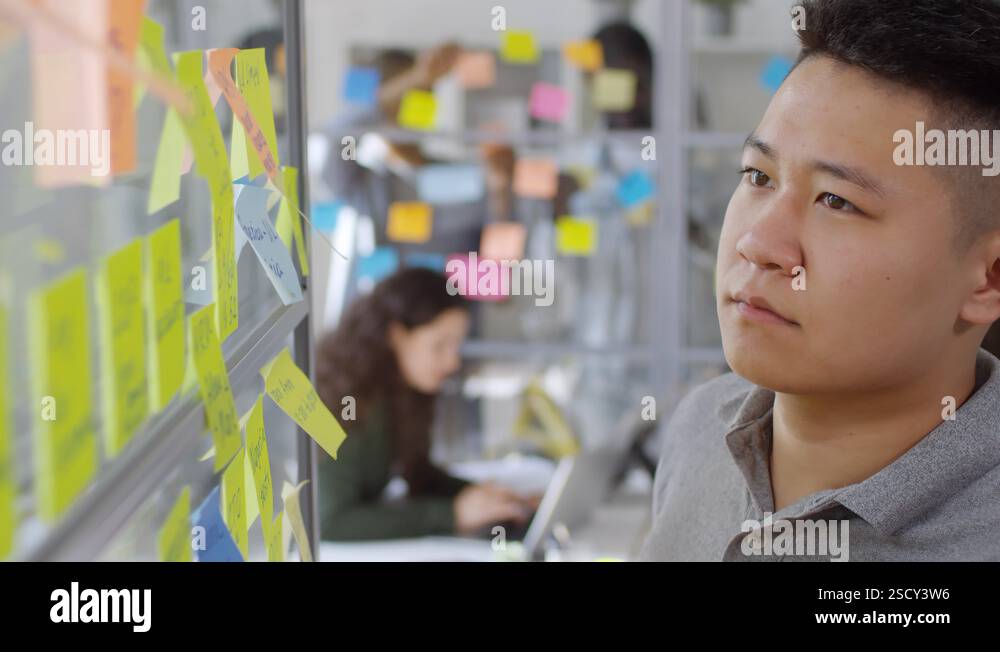 Young Asian Man Taking off adhesive Notes from Glass Wall in Office ...