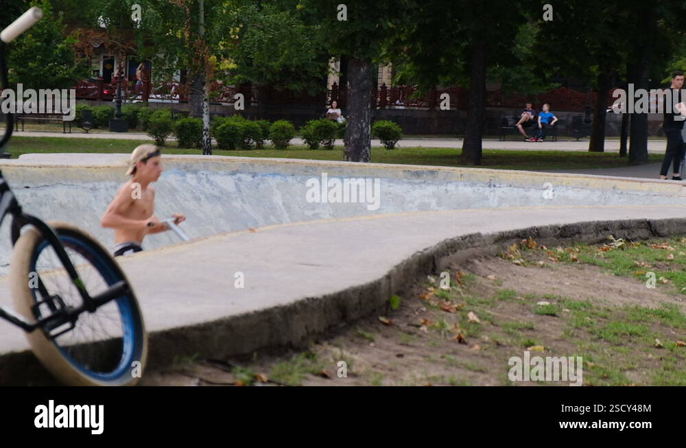 A young guy jumps and does tricks on a scooter in a skatepark Stock ...