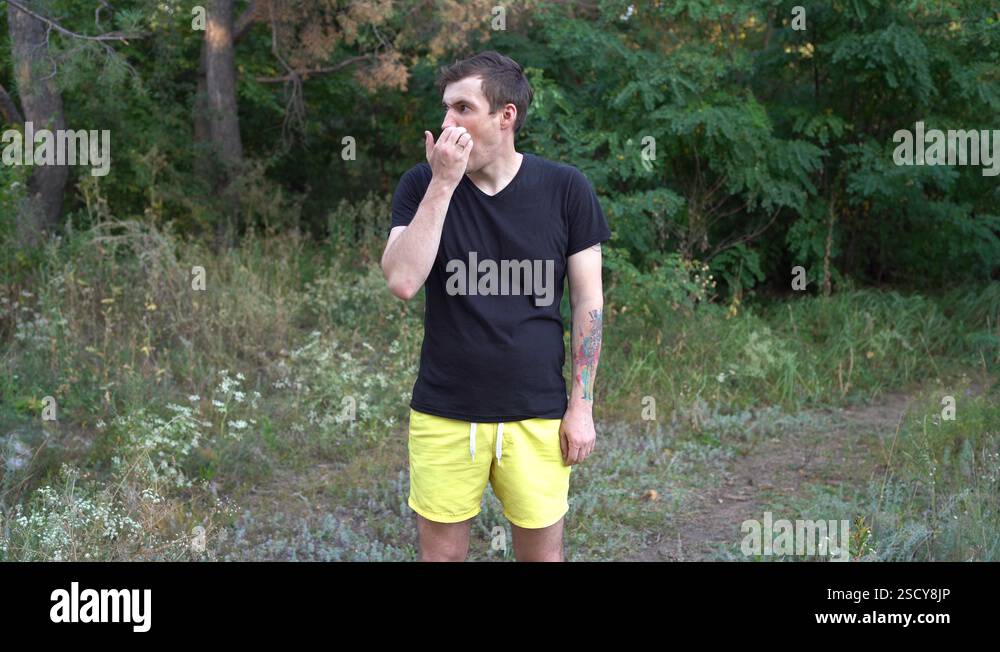 A young handsome man in casual clothes is scratching his chin and ...