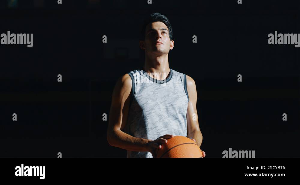 Cinematic shot of an young male player is making a slam dunk in a gym ...