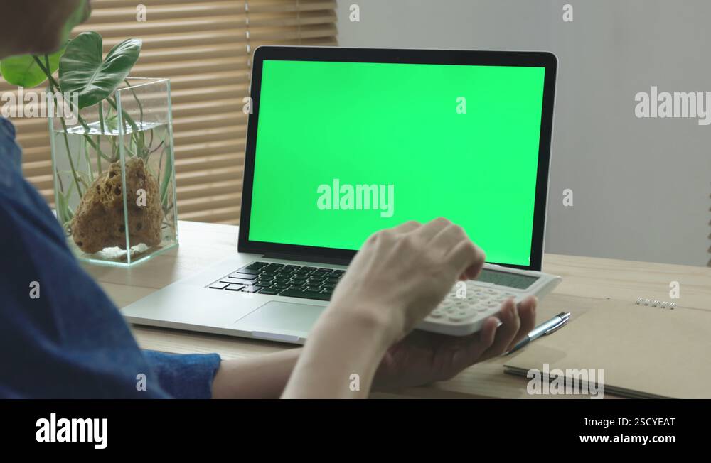 Over the shoulder shot of man typing on laptop keyboard with green ...