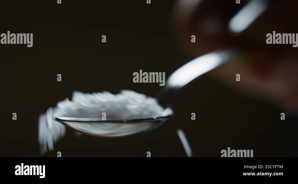 Close up of the hand of a chef while dropping salt with a tea spoon ...