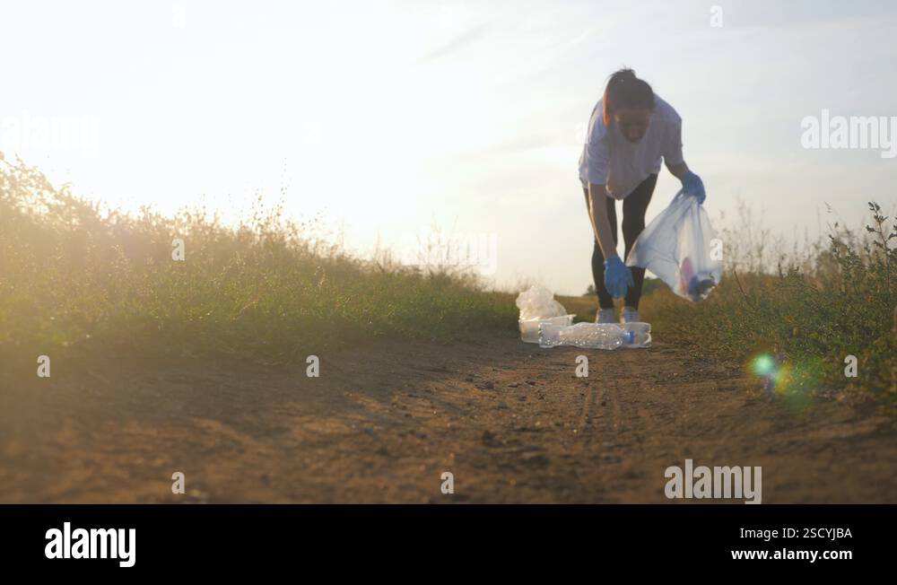 Care about nature. Volunteer girl collects trash in the trash bag ...