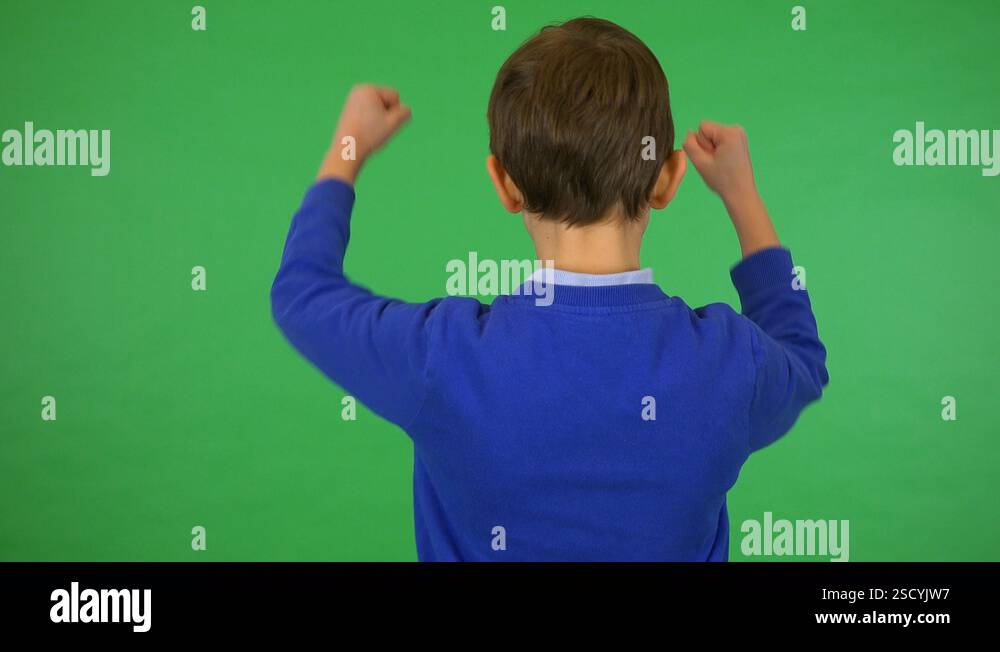 A young cute boy is turned with back to the camera, looks at the green ...