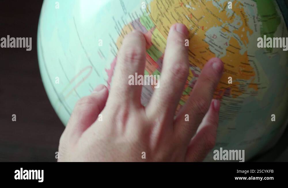 Hand rotating globe to find American continent. Atlas and Geography ...