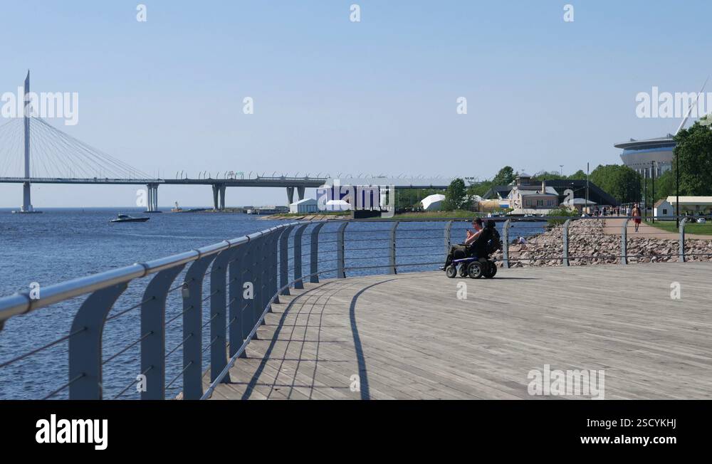 disabled man in a wheelchair on the embankment overlooking the bridge ...