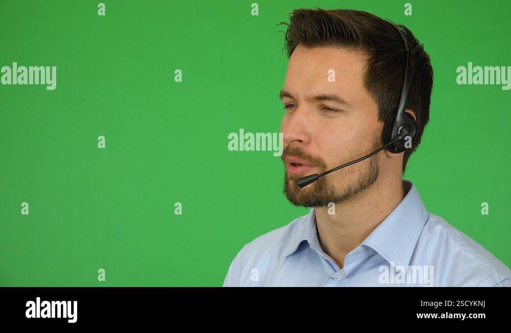 A young handsome call center agent talks to a caller with a smile ...