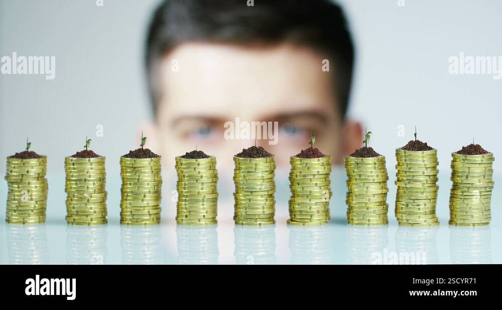 A businessman in a suit and tie with stacks of gold coins behind Stock ...