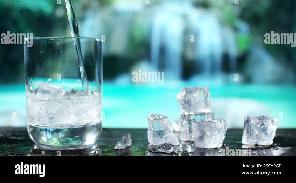 A pure fresh water is poured into a glass on background of nature Stock ...