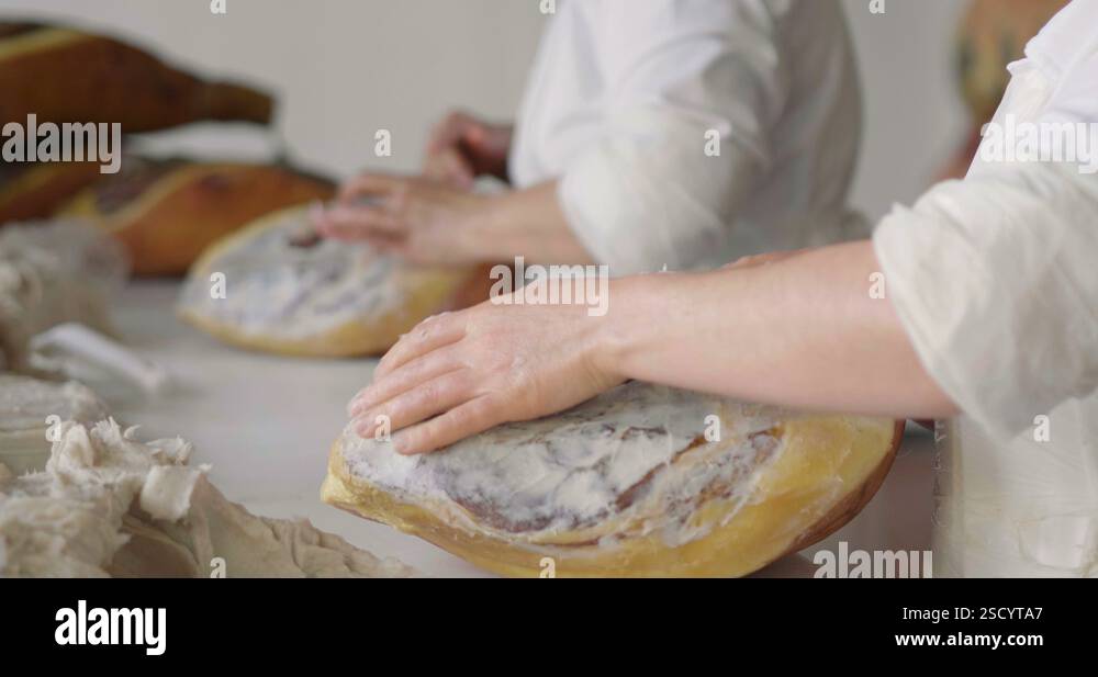 Close-up of an expert hand is gathering a ham with fat before seasoning ...