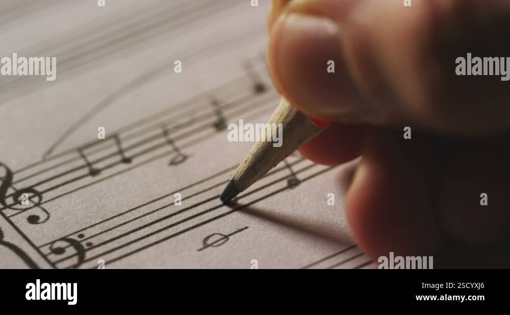 Close up of musician composer is writing the notes of his new song ...