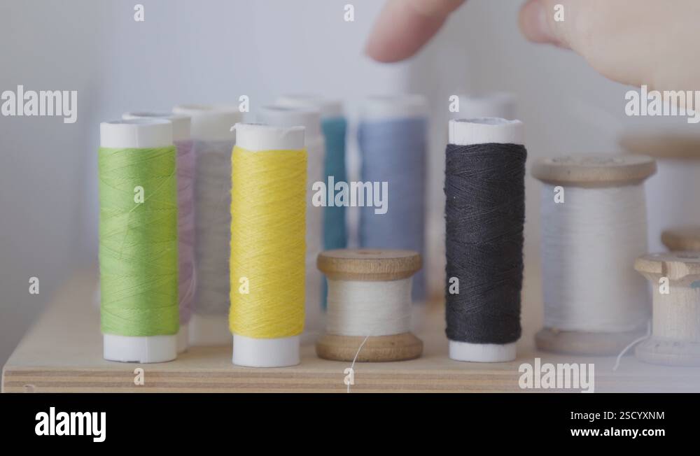 Close-up of female hand choosing the thread for sewing. The woman ...
