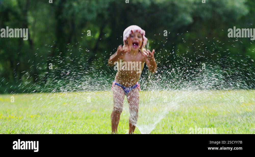 A toddler baby girl is playing with water and enjoying bathing on a ...