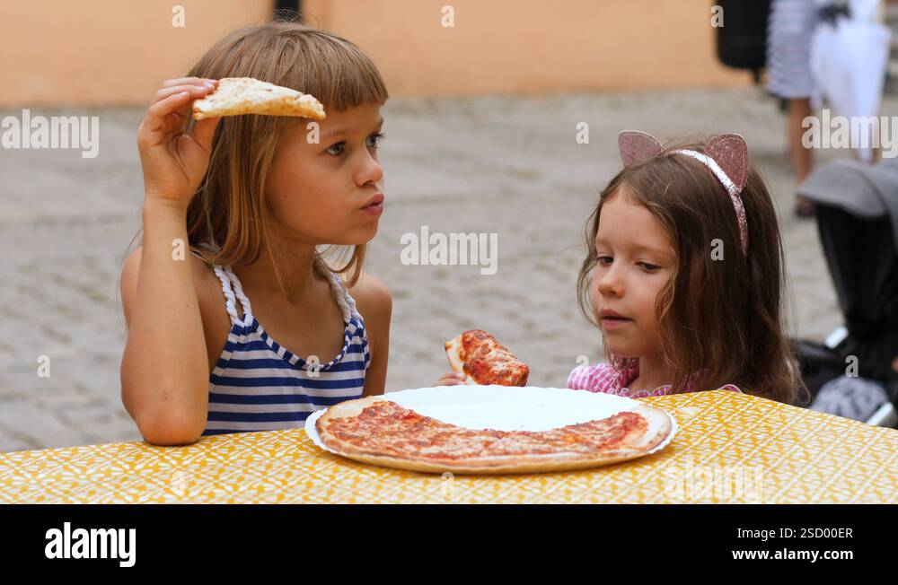 Two children girls eat street food pizza on festival day outdoors ...