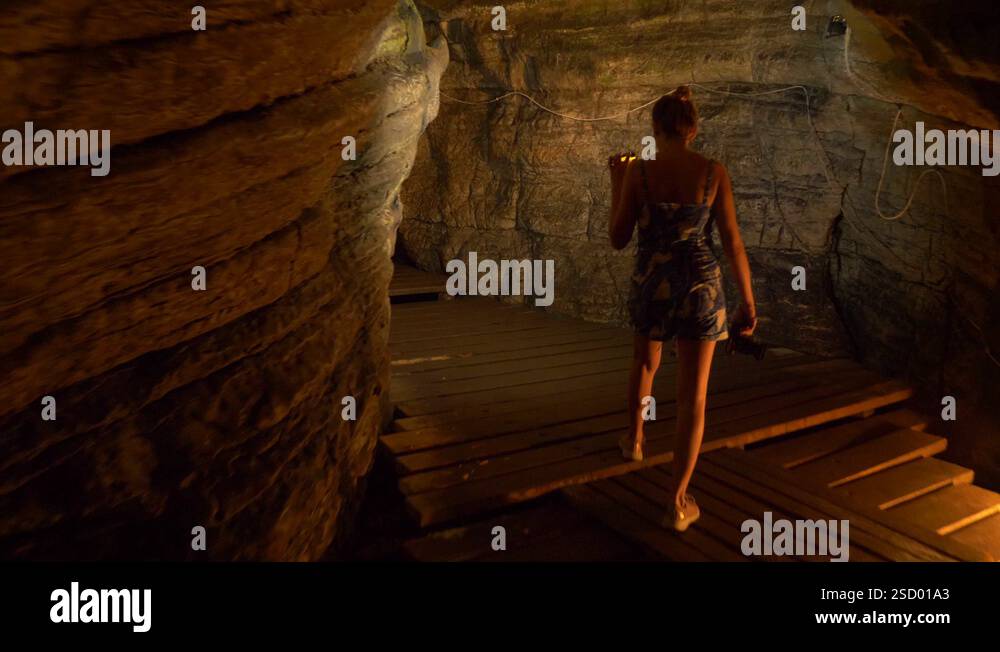 woman tourist with a lantern passes inside a cave with artificial ...