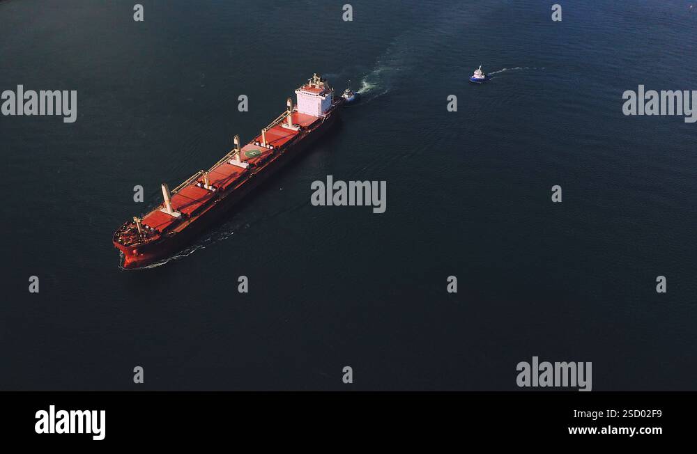 Aerial rising over tanker vessel sailing in ocean beeing escorted by ...