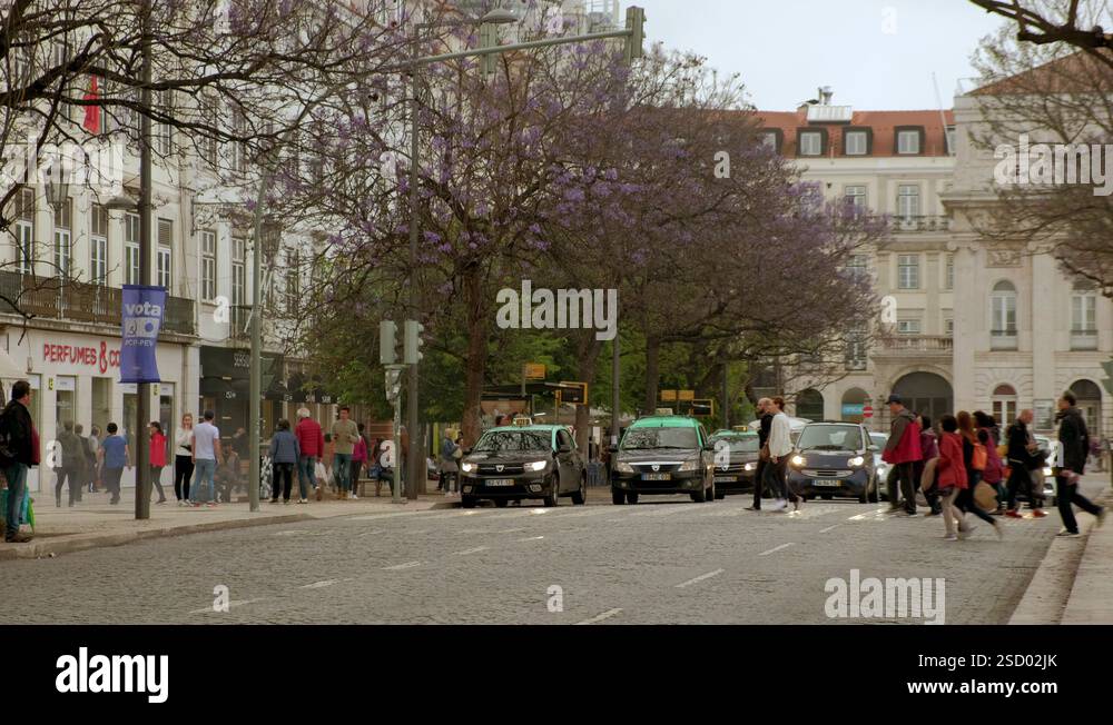 Static clip of people passing crosswalk and cars driving through Rossio ...
