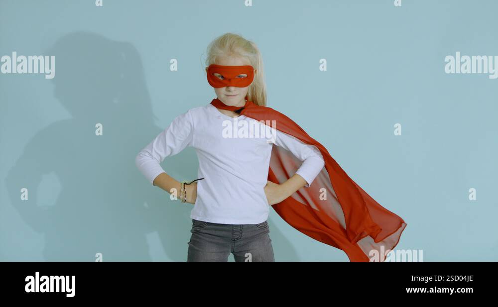Caucasian girl wearing red cape and mask, pretending to be a superhero ...