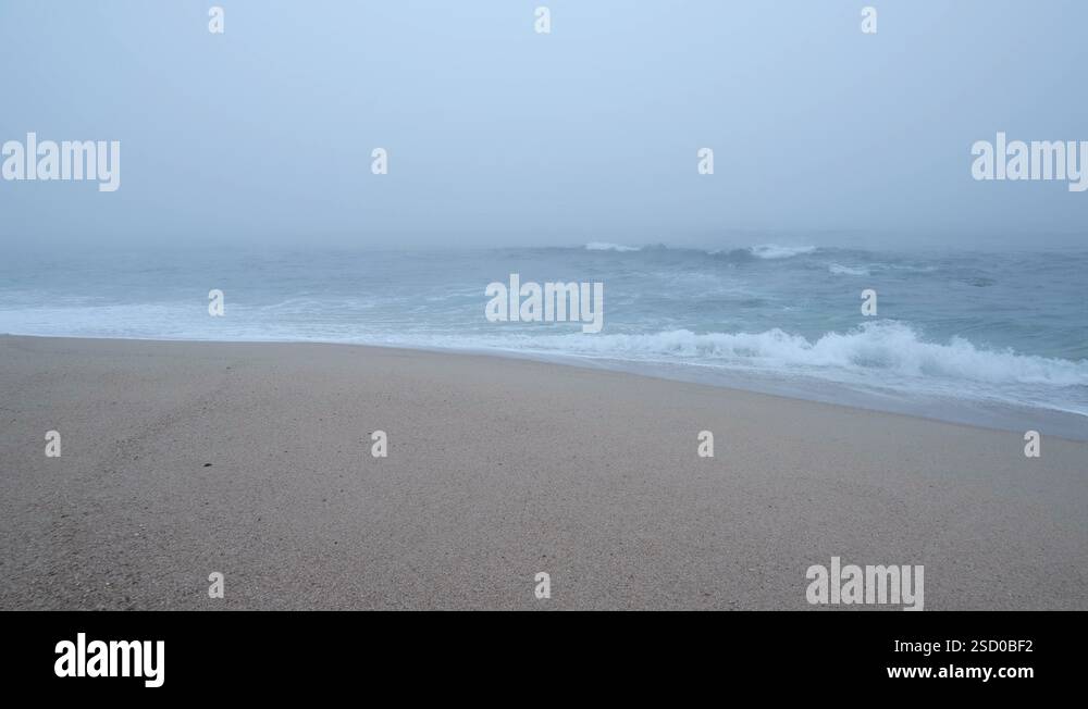 Very misty day at the beach, with thick fog over the ocean. Pan right ...