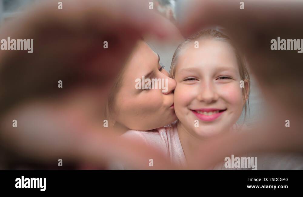 Happy face of attractive young mother kissing cute teen daughter making heart Stock Video ...