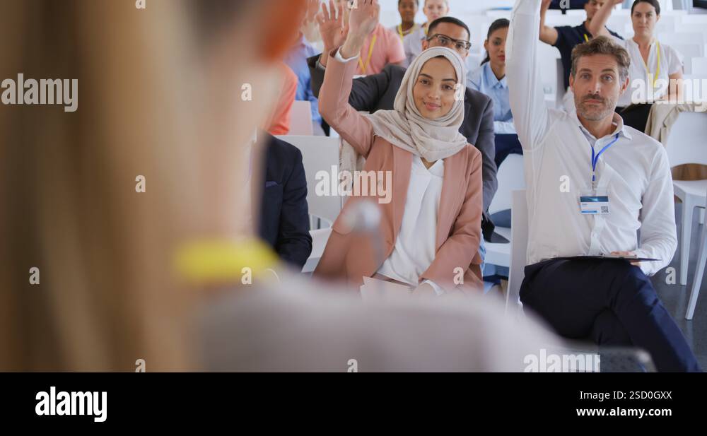 Audience at a business presentation raising their hands to ask ...