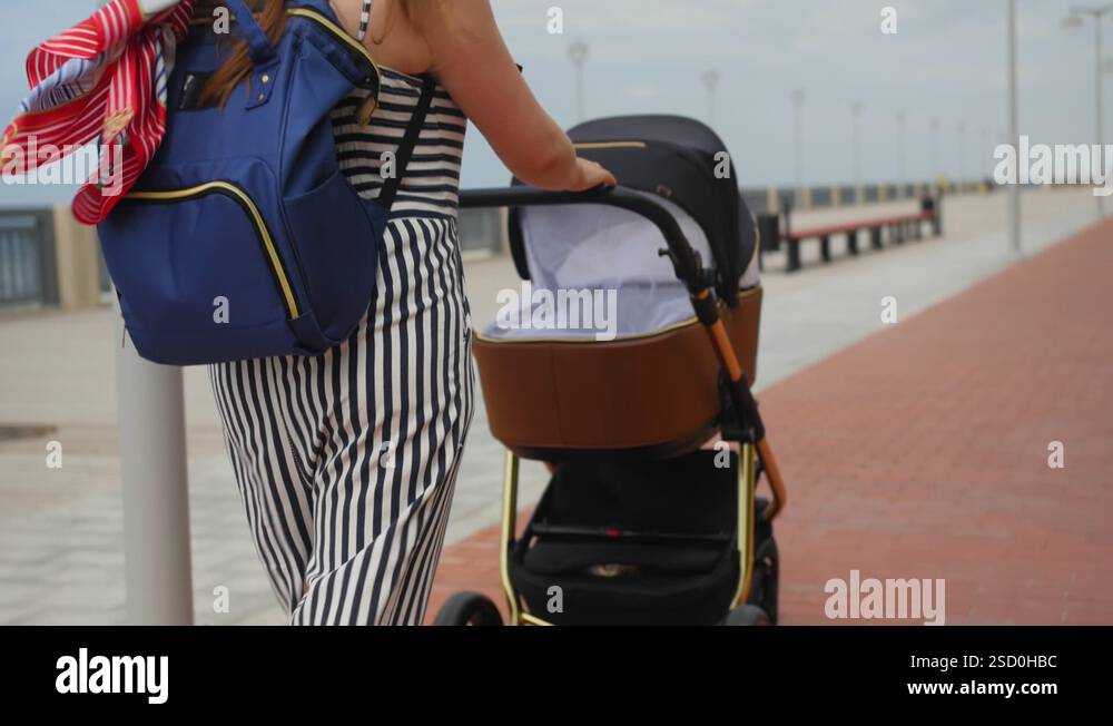 Modern mother walks with a pram at promenade. Family, motherhood and ...