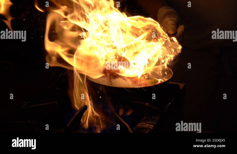 Chef frying vegetables on fire throwing them in a frying pan. Slow ...