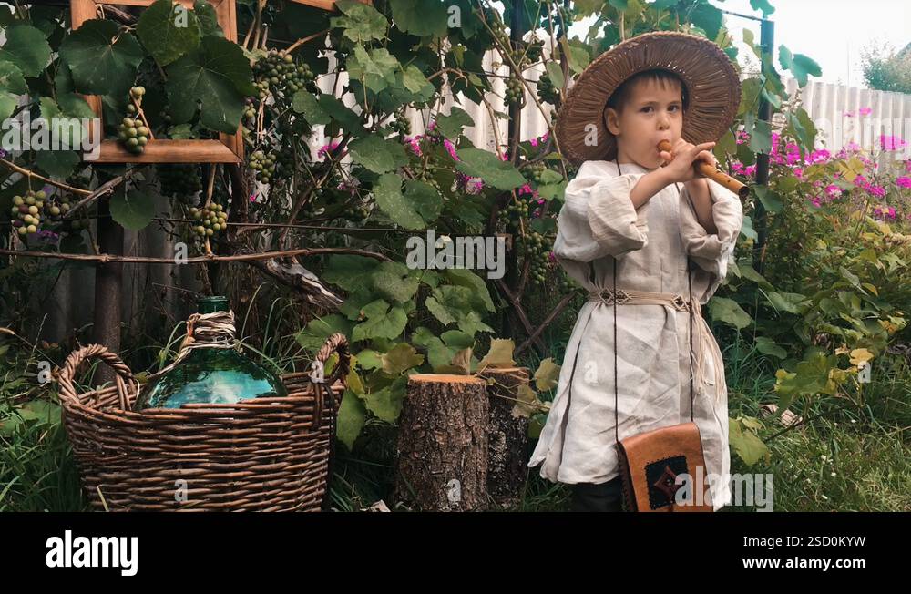 Charming cute caucasian child in village clothes and hat having fun in ...