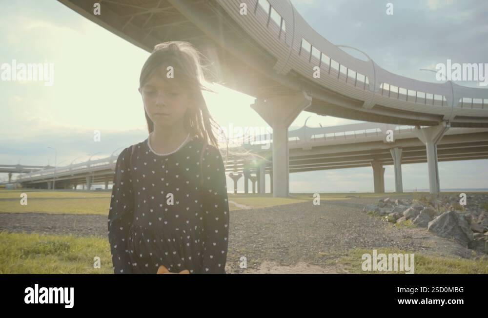 Nice small girl walking and playing with her toy cat under a bridge in ...