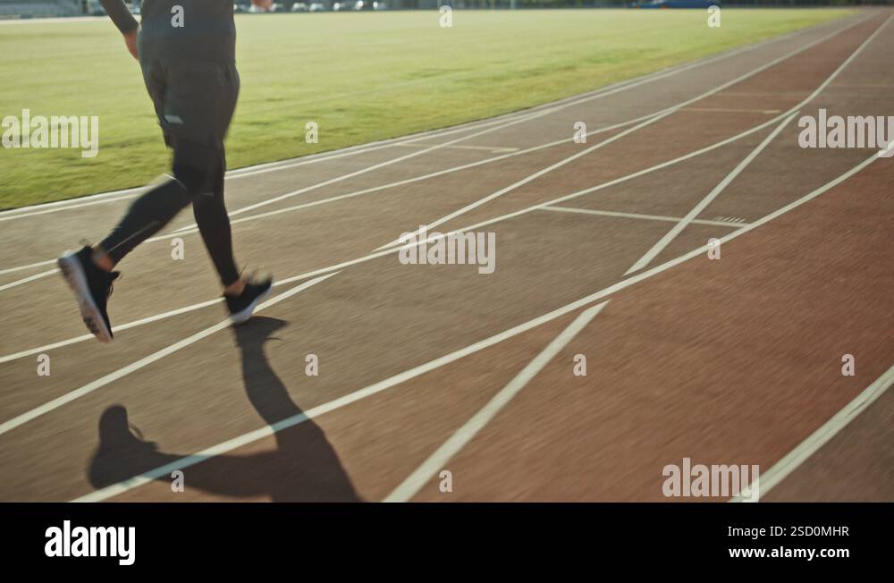 Athletic Fit Man in Grey Shirt and Shorts Jogging in the Stadium. He is ...