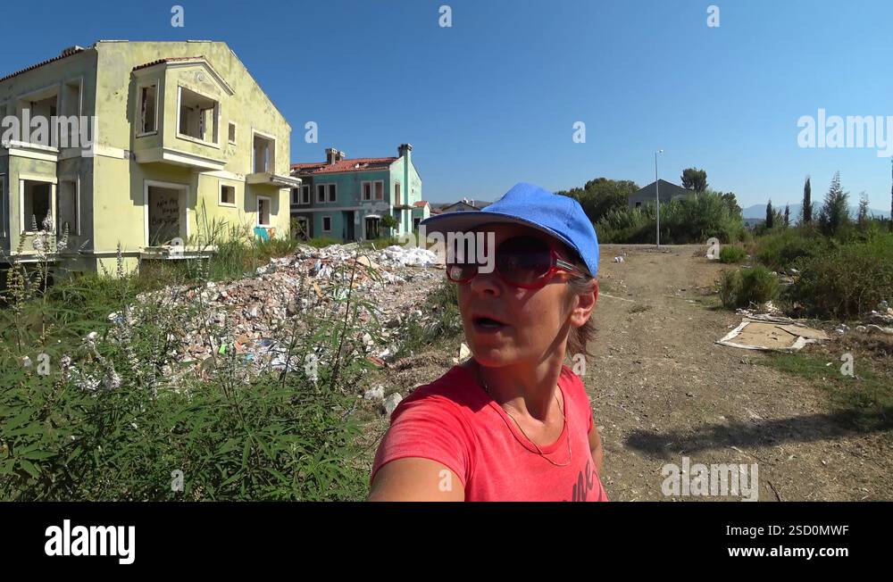 Woman environmentalist shows heap of waste and derelict houses 2 Stock ...