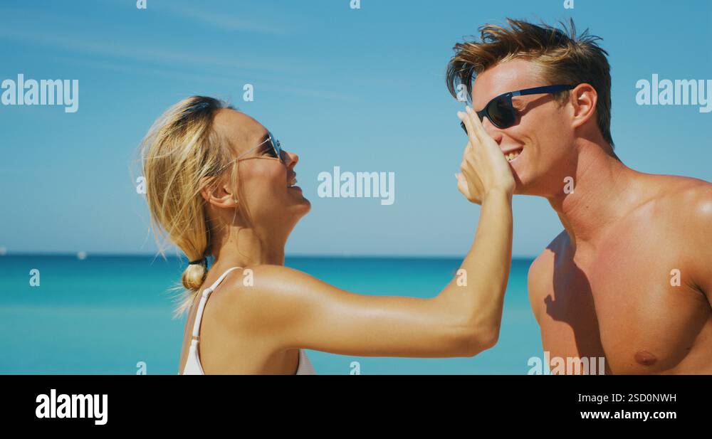 Happy young couple is having fun to apply a sunscreen on a beach Stock ...