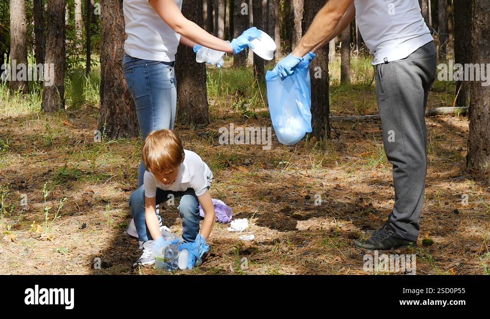 Family activists collect garbage in the woods. The child puts the ...