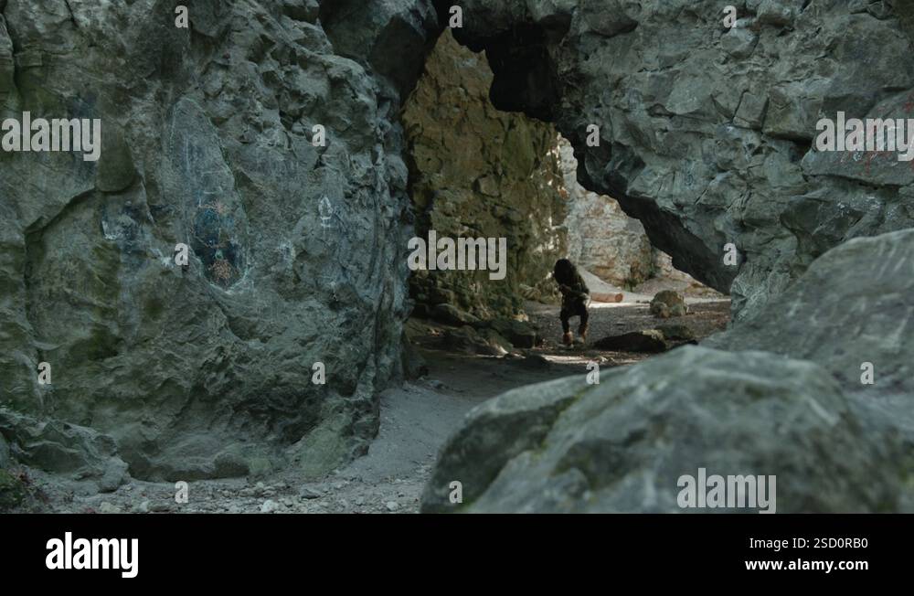 African neanderthal hunter-gatherer in animal fur walking slowly in ...