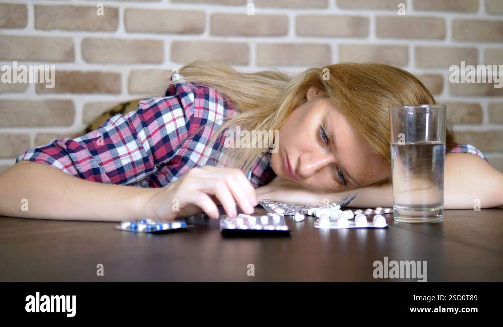 sick sad woman is sorting pills while sitting at the table. healthcare ...