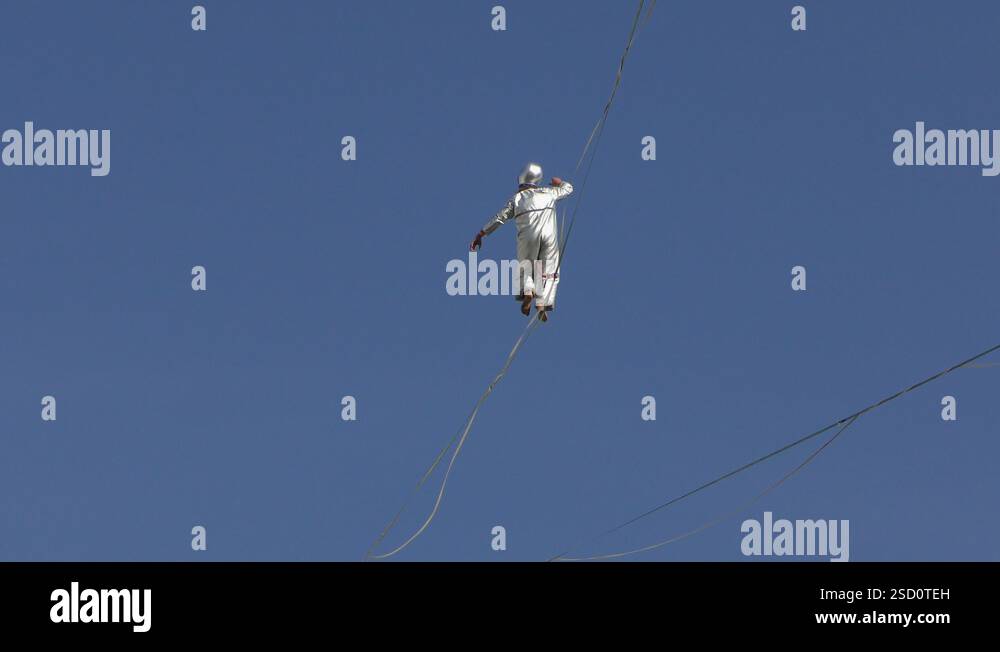 A tightrope walker in an astronaut costume reaches the end of the rope ...
