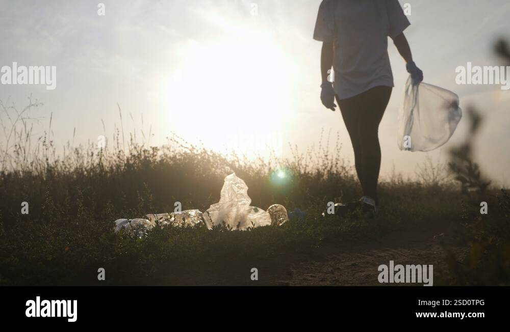 Care about nature. Volunteer girl collects trash in the trash bag ...