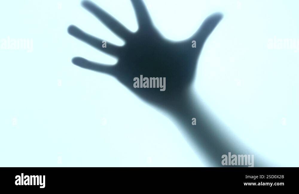 Dark hand silhouette moving slowly behind a light blue glass Stock ...