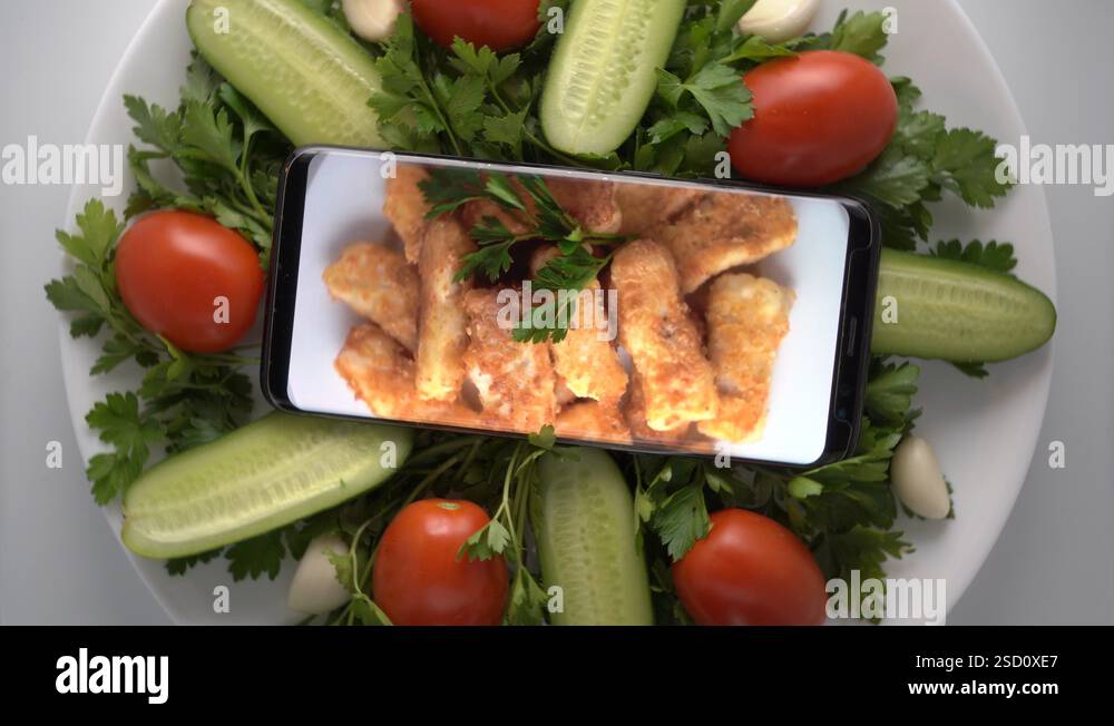 Plate with salad and cellphone with crispy fried cod fish fillet on ...
