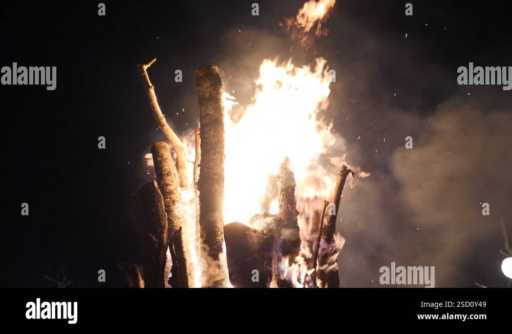 Fire flames and moke of big campfire go to dark night sky. Low angle ...