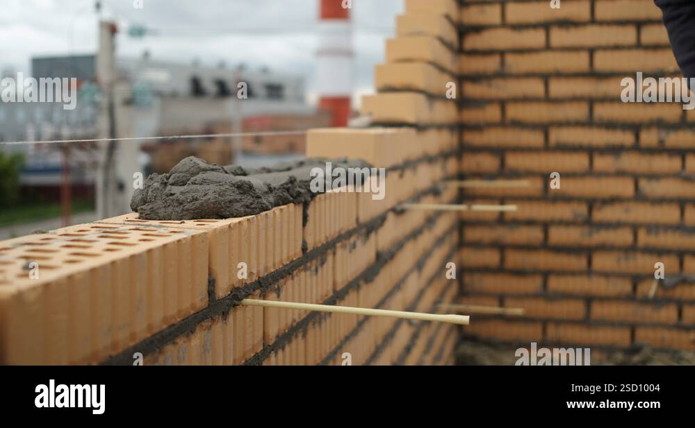 Mason erects a wall of a brick building in the industrial zone of the ...