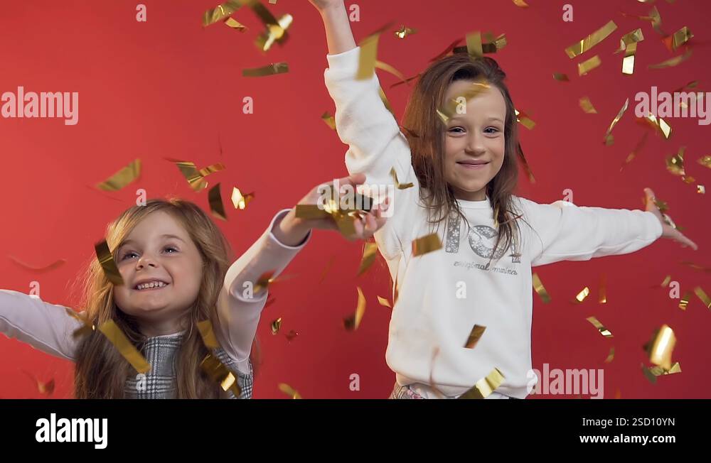 Slow motion of pretty little girls throwing golden confetti on the red ...