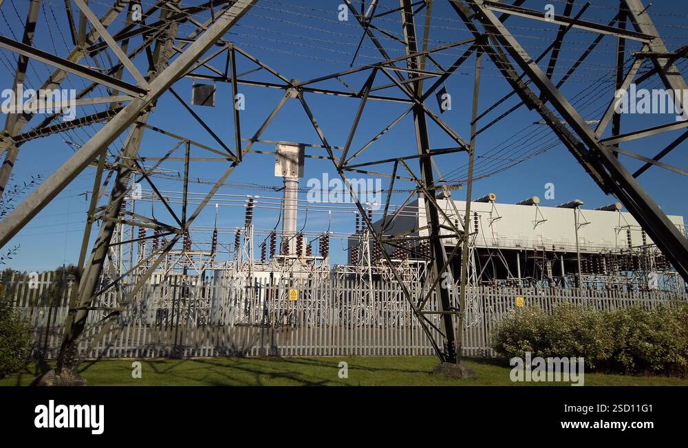 Pan across overhead electricity grid pylon and a gas fired power ...