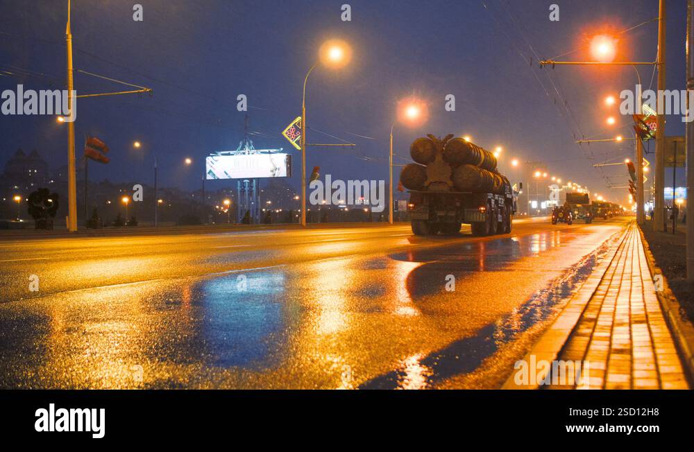 A convoy of military equipment rides through the city at night with ...
