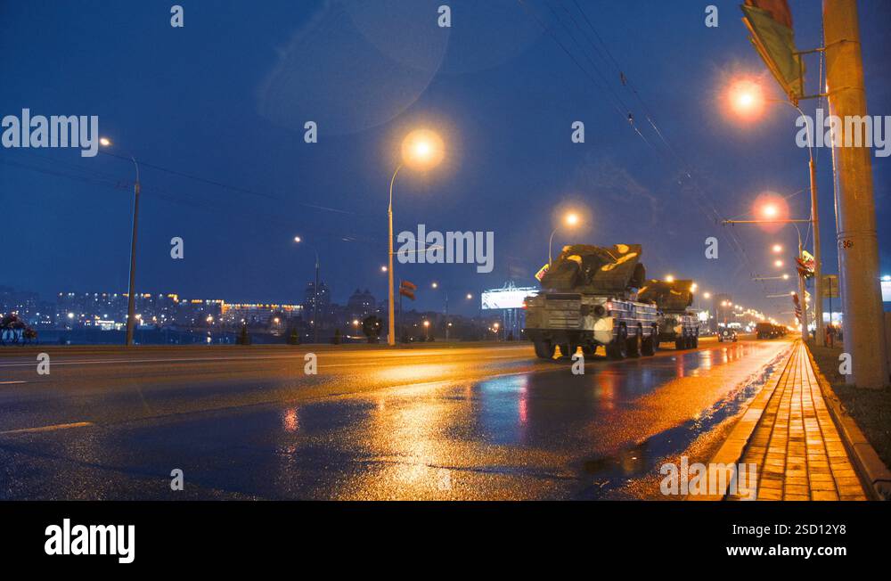 A convoy of military equipment rides through the city at night with ...
