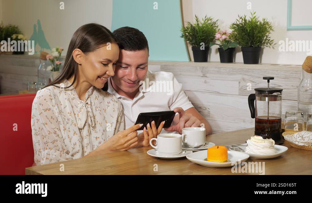 girl and guy looks at mobile phone at table in sweet shop Stock Video ...