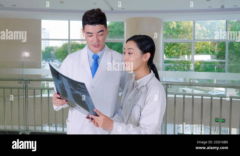 MS Male and female doctors discussing X-ray image and smiling at camera ...