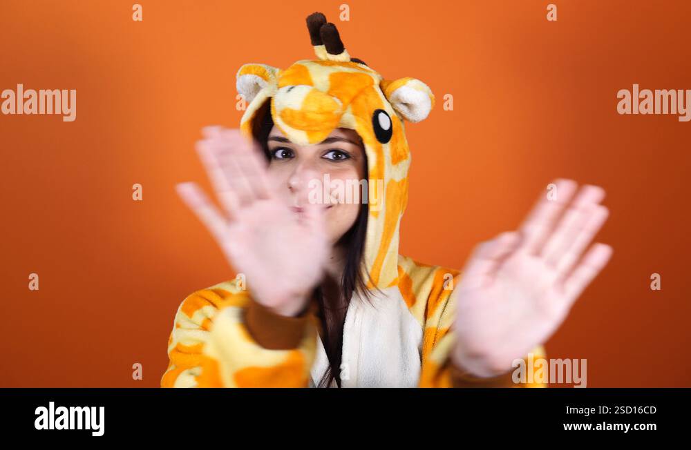A funny woman in a big kigurumi of giraffe shows a stop sign which ...